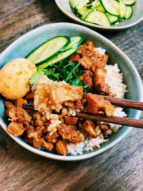 Two Bowls Filled With Rice Meat And Veggies On Top Of A Wooden Table