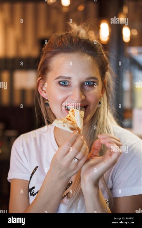 Casual Girl Eating Pizza In The Restaurant And Enjoying This Funny Blonde Girl In White T Shirt