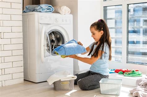 Niña feliz lavando ropa en el interior de una casa Foto Premium