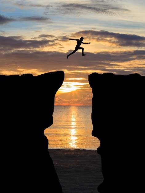 Hombre Saltando Sobre Un Acantilado Al Atardecer Foto Premium