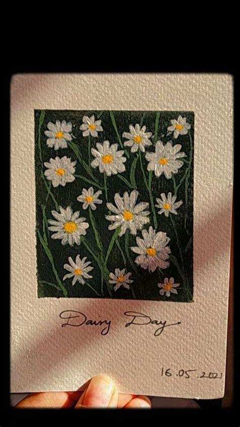 A Painting Of Daisies Is Being Held By Someone S Hand In Front Of Them