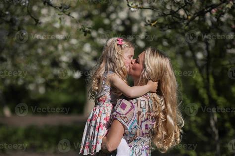 Daughter Kisses Mom In The Garnde Stock Photo At Vecteezy