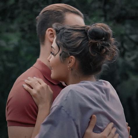 A Man And Woman Embracing Each Other In Front Of Trees