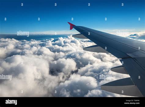 Wing Of An Airplane Flying Above The Sky With Clouds Above The Ocean