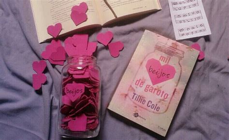 A Jar Filled With Pink Hearts Next To An Open Book