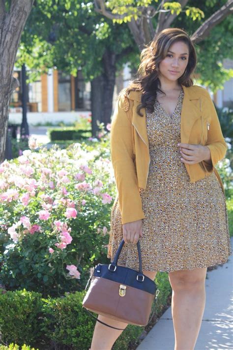 A Woman Is Standing On The Sidewalk Holding A Purse