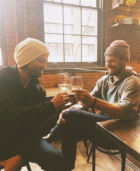 Two Men Sitting At A Table With Wine Glasses