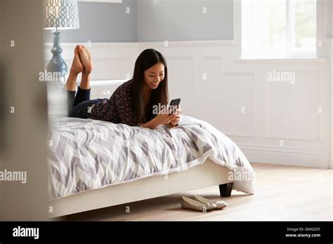 Woman Relaxing On Bed Checking Mobile Phone Stock Photo Alamy
