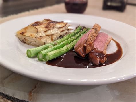 A Plate With Meat Asparagus And Gravy On It Sitting On A Table