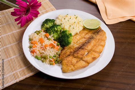 Filé de Peixe arroz a grega maionese e salada de brócolis em mesa