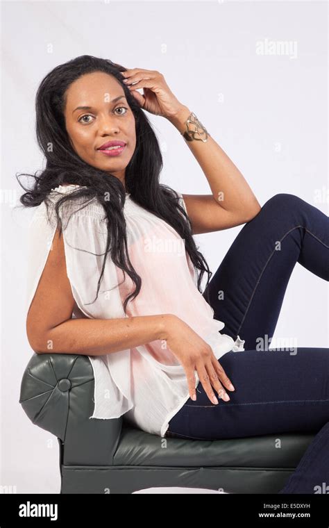 Black Woman Sitting On A Bench With One Elbow On Her Knee Looking At