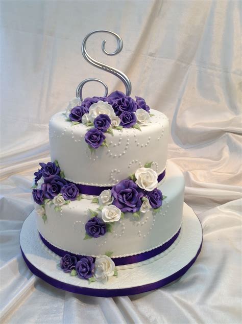 Two Tiered Wedding Cake With Purple And White Flowers On The Bottom