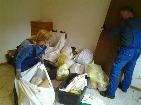 Two People In Blue Work Together To Clean Up The Floor With Trash Bags