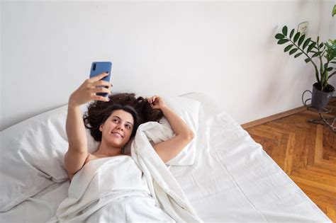 Premium Photo Woman Laying In Bed Taking Selfie On The Phone