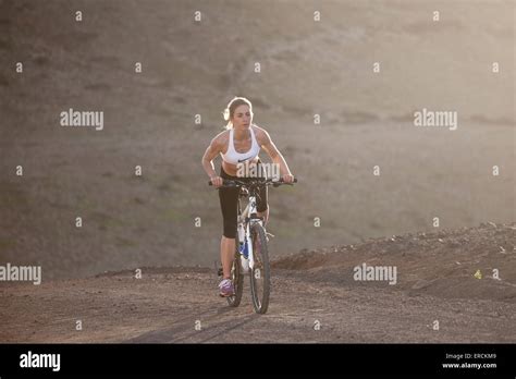 A Blonde Girl Rides Her Bike Uphill On A Rocky Place In Fuerteventura Canary Islands Stock