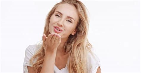 Young Beautiful Caucasian Blonde Girl Blowing A Kiss Picturing Imaginary Heart Smiling Shy On