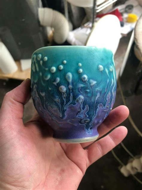 A Hand Holding A Blue And Purple Cup With White Bubbles On It S Rim