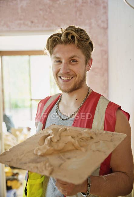 Retrato sonriente joven trabajador de la construcción confiado