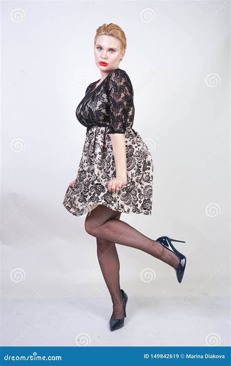 Cute Chubby Girl In Short Modern City Dress Made Of White Fabric And Black Lace Posing In