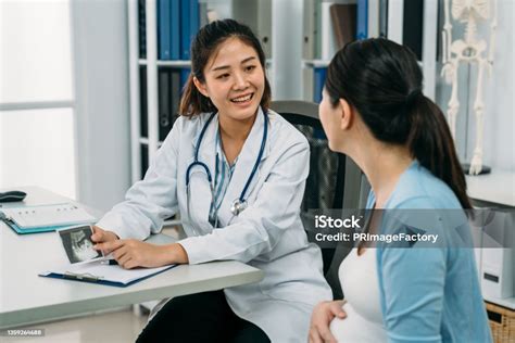 Asian Female Gynecologist Is Smiling While Showing And Explaining An Ultrasound Picture To Her