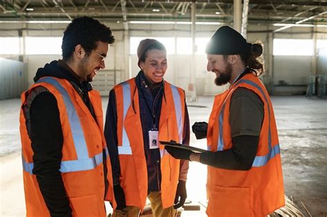 Tres jóvenes trabajadores felices del almacén discutiendo puntos de