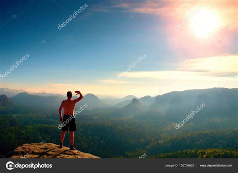 Hombre desnudo en pantalones negros solo en la cima de la montaña al