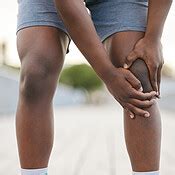 A Man Grabbing His Knee In Pain From Exercising An African American