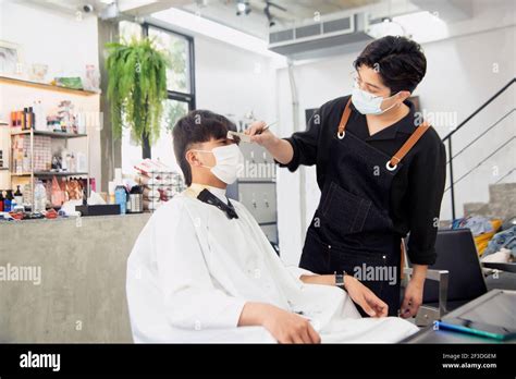 Asian Male Hairdresser Make Hairstyles For Asian Male Customers In Modern Beauty Salons In