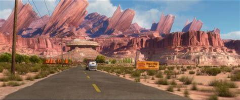 A Car Is Driving Down The Road In Front Of Some Mountains And Rock