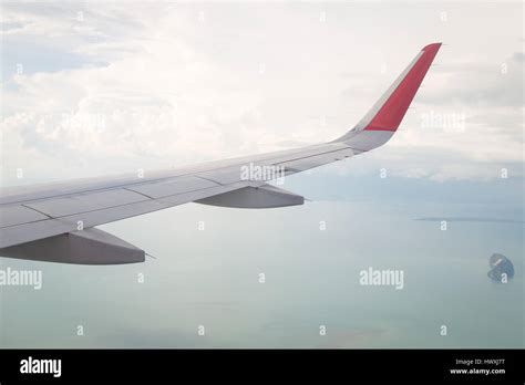 Wing Of An Airplane Flying Above The Ocean And Many Island Stock Photo