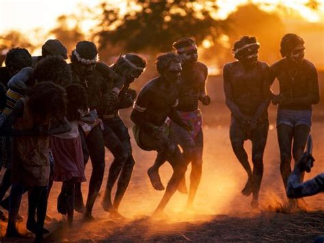 A Group Of People Are Dancing Around In The Dirt With Fire Coming From