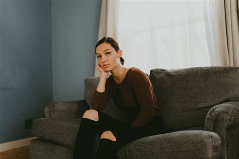 A Woman Sitting On Top Of A Couch Next To A Window