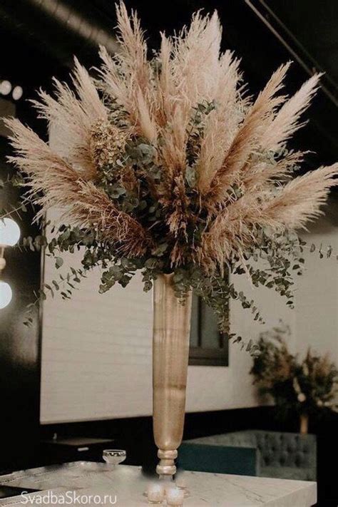 A Tall Vase Filled With Flowers On Top Of A Table