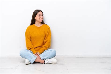Chica Joven Sentada En El Suelo Aislado Sobre Fondo Blanco Mirando