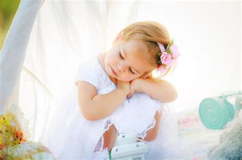Niña hermosa se sentó en cuclillas y abrazó las manijas de las rodillas