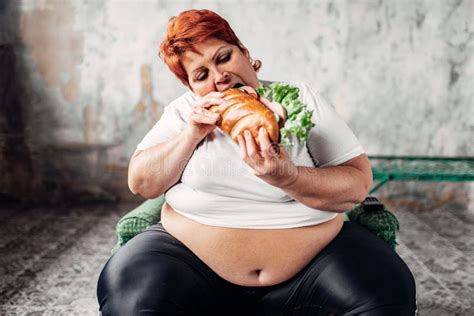 Fette Frau Sitzt Im Stuhl Und Isst Das Sandwich Bulimisch Stockfoto