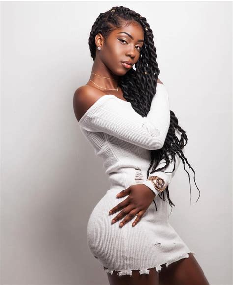 A Woman In A White Dress Posing For The Camera With Her Hand On Her Hip