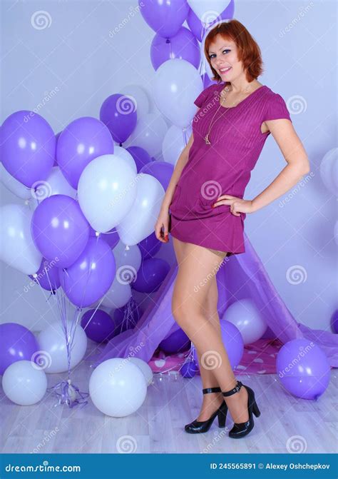 Beautiful Long Legged Redhead Girl In Violet Dress And Shiny Stockings Posing At The Ball Stock