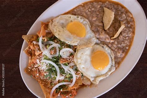 Plato De Chilaquiles Con Dos Huevos Estrellados Y Frijoles Stock Photo
