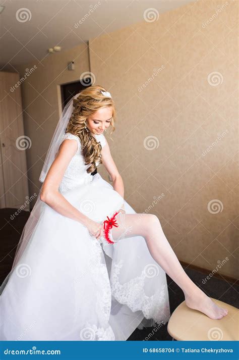 Bride Putting A Wedding Garter On Her Leg Stock Photo Image Of Belt