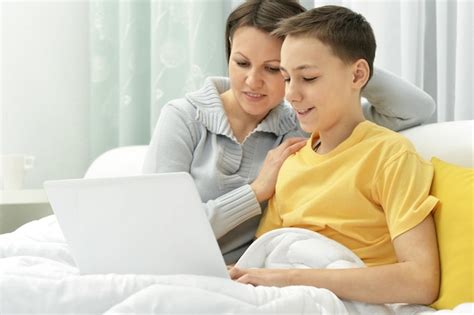 Premium Photo Mother And Son Sitting On Bad And Using Laptop