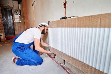 Plombier En Combinaison De Travail Installant Un Radiateur De Chauffage