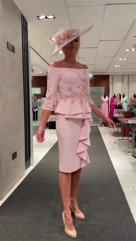 A Woman In A Pink Dress And Hat Walking Down A Hallway