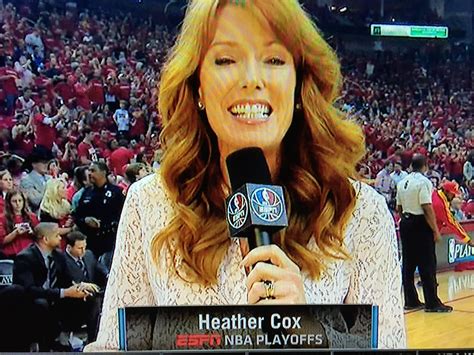 A Woman Holding A Microphone In Front Of A Crowd At A Basketball Game