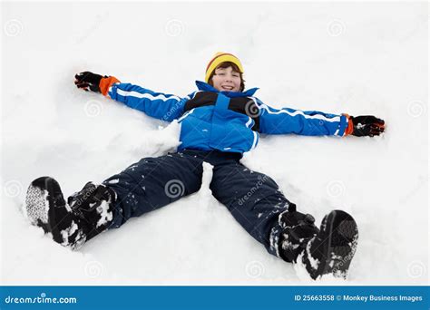 Menino Novo Que Faz O Anjo Da Neve Na Inclinação Foto de Stock Imagem