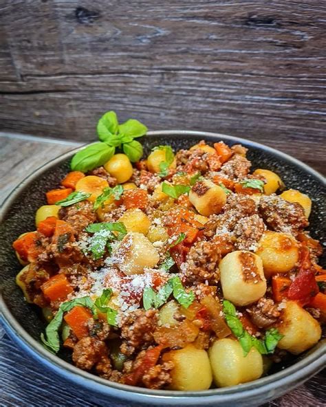 A Close Up Of A Bowl Of Food On A Wooden Table With Parmesan Cheese