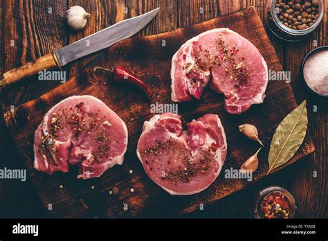 Pork Loin Steaks With Ground Spices On Rustic Cutting Board Stock Photo