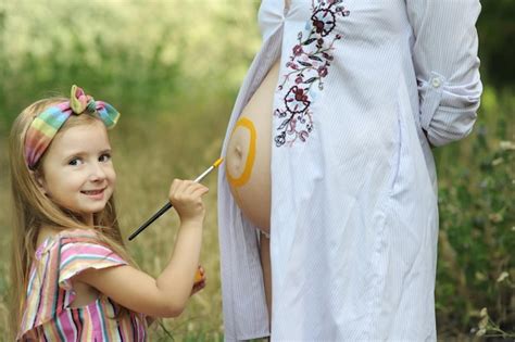 Menina pintando sol na barriga da mamãe grávida Foto Premium