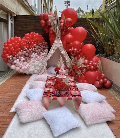 A Table Topped With Lots Of Red And White Balloons