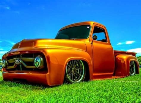 An Orange Truck Parked On Top Of A Lush Green Field